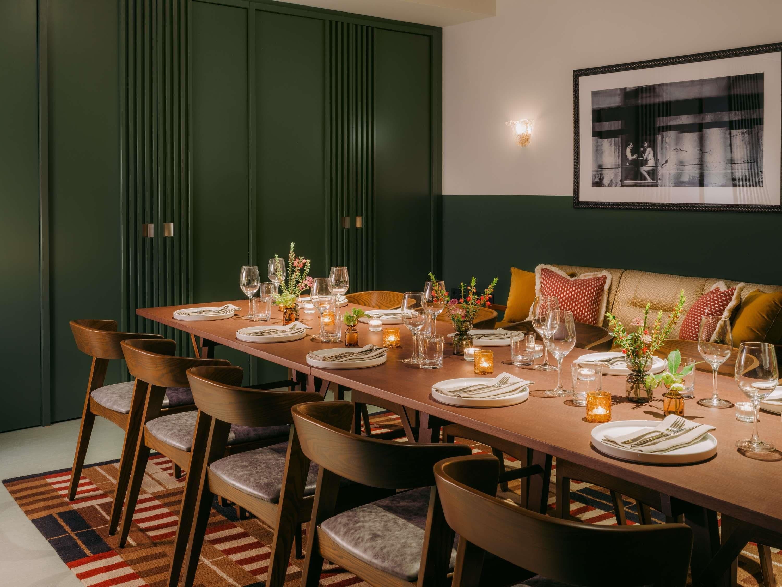 Uma sala de jantar com uma mesa comprida posta para refeição, rodeada por cadeiras.