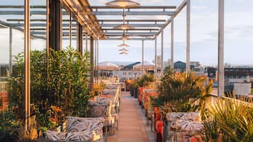 Terraço no telhado com área de estar ao ar livre, pérgola e vista panorâmica da cidade.