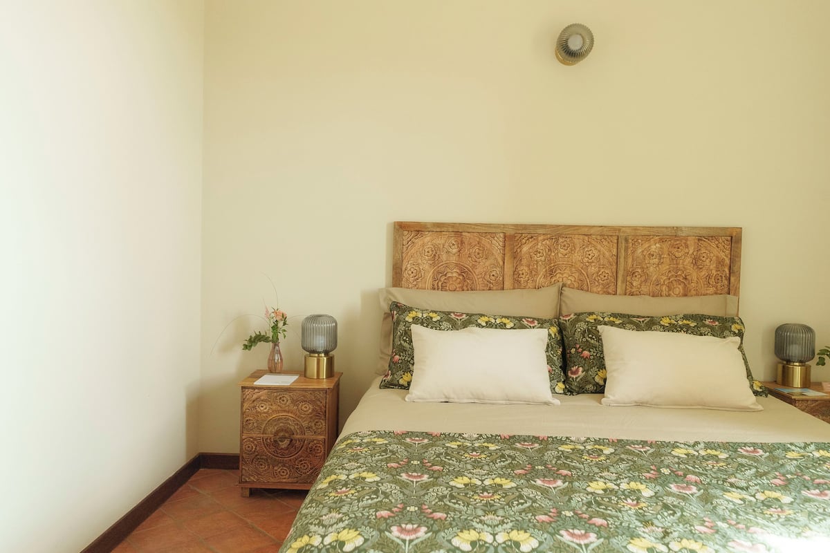 Quarto bem arrumado com cama, duas mesas de cabeceira e cabeceira decorativa.