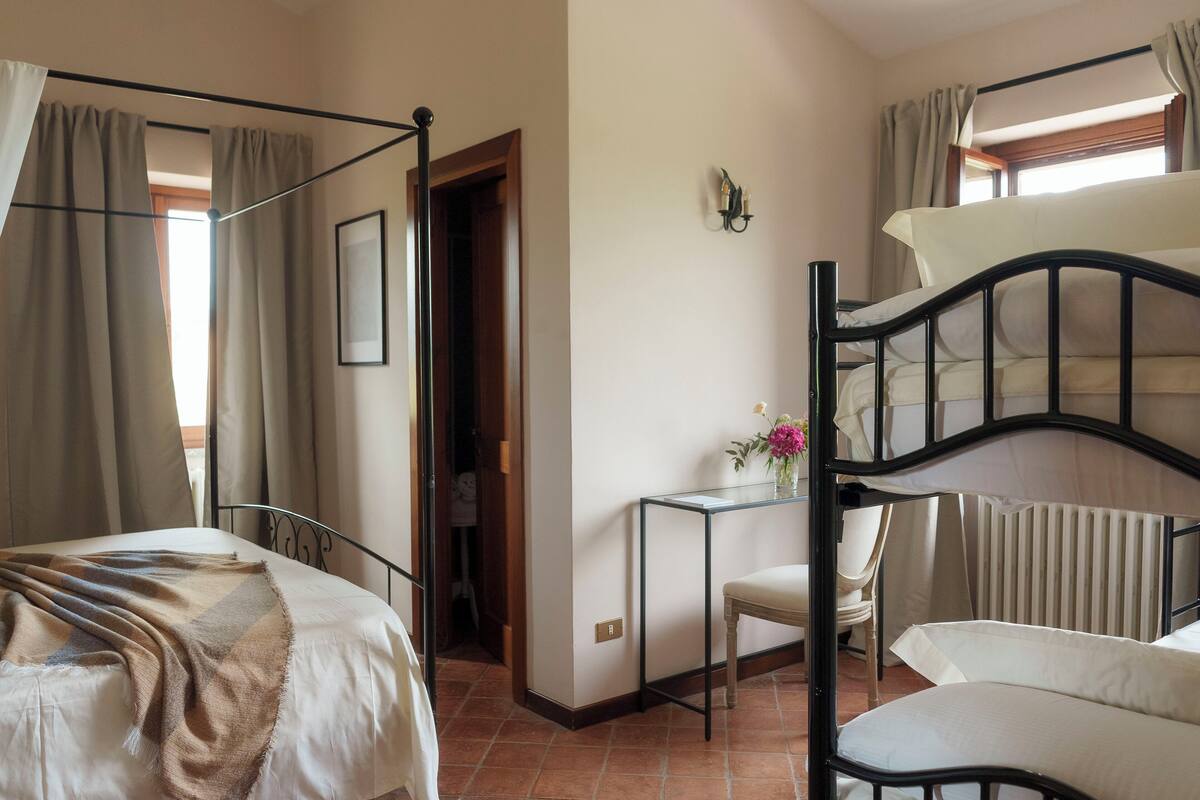 Quarto com cama de dossel, escrivaninha e cadeira, e radiador.