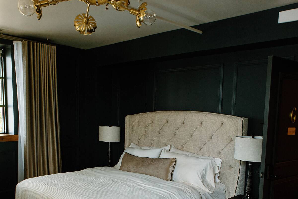 Quarto com uma cama grande, um candelabro e uma mesa de cabeceira com abajur.