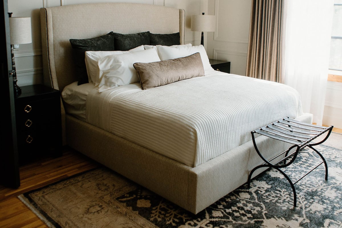 Quarto bem arrumado com uma cama grande, mesa de cabeceira, abajur e luminária pendente.