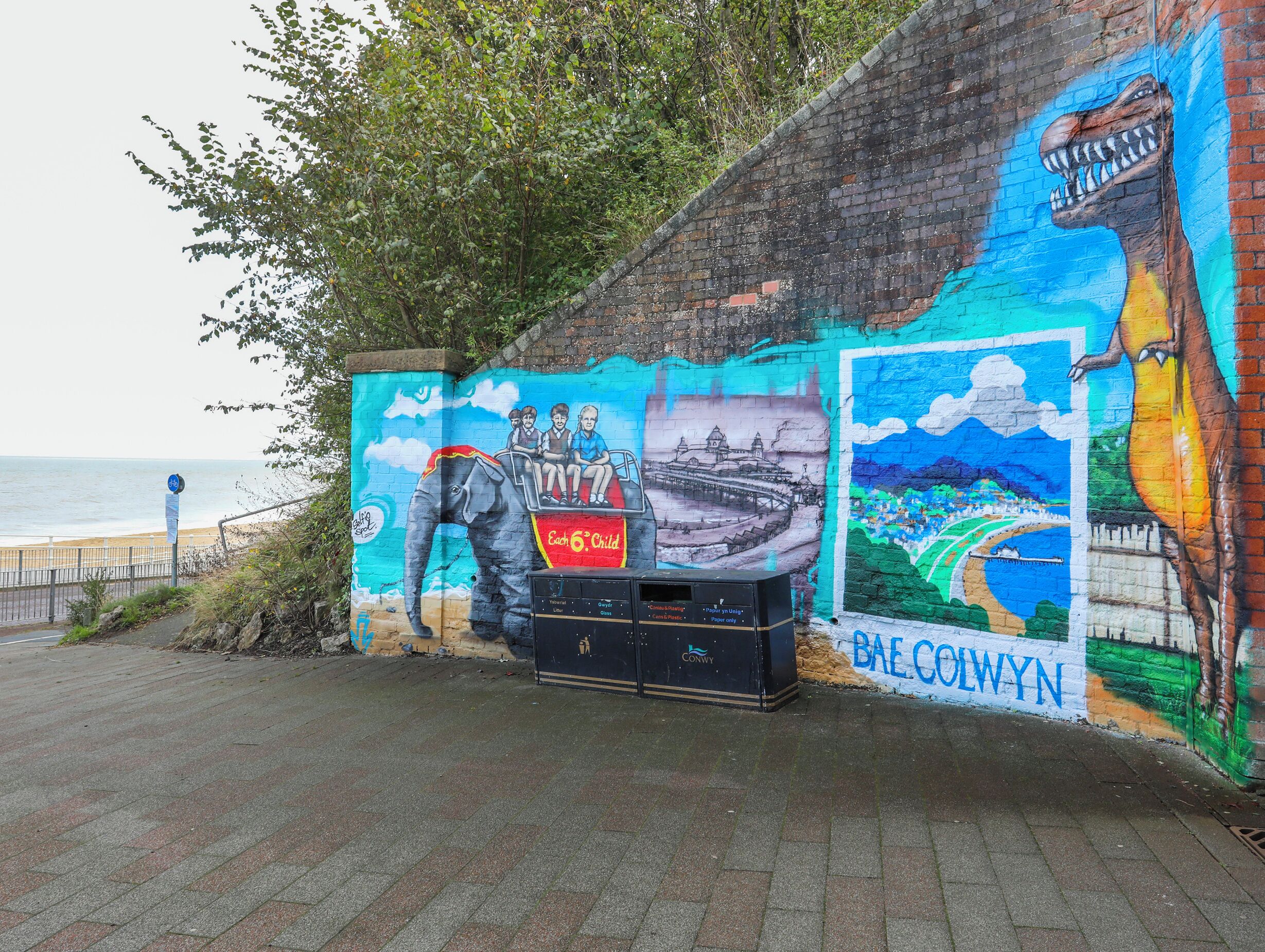 Um mural com um dinossauro, um elétrico e uma cena de praia.