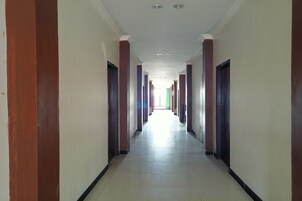 Um corredor comprido e estreito com colunas vermelhas e azuis alternadas, que leva a uma saída iluminada.