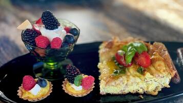 Um prato de sobremesa com uma fatia de quiche e três miniaturas de torta, cada uma coberta com chantilly e frutas vermelhas.
