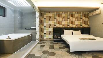 Quarto de hotel moderno com banheiro, uma cama e um painel de cabeceira estampado, e piso revestido de azulejos.