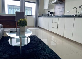 Uma cozinha moderna com armários brancos, bancada preta e uma mesa de centro de vidro com uma planta em vaso.