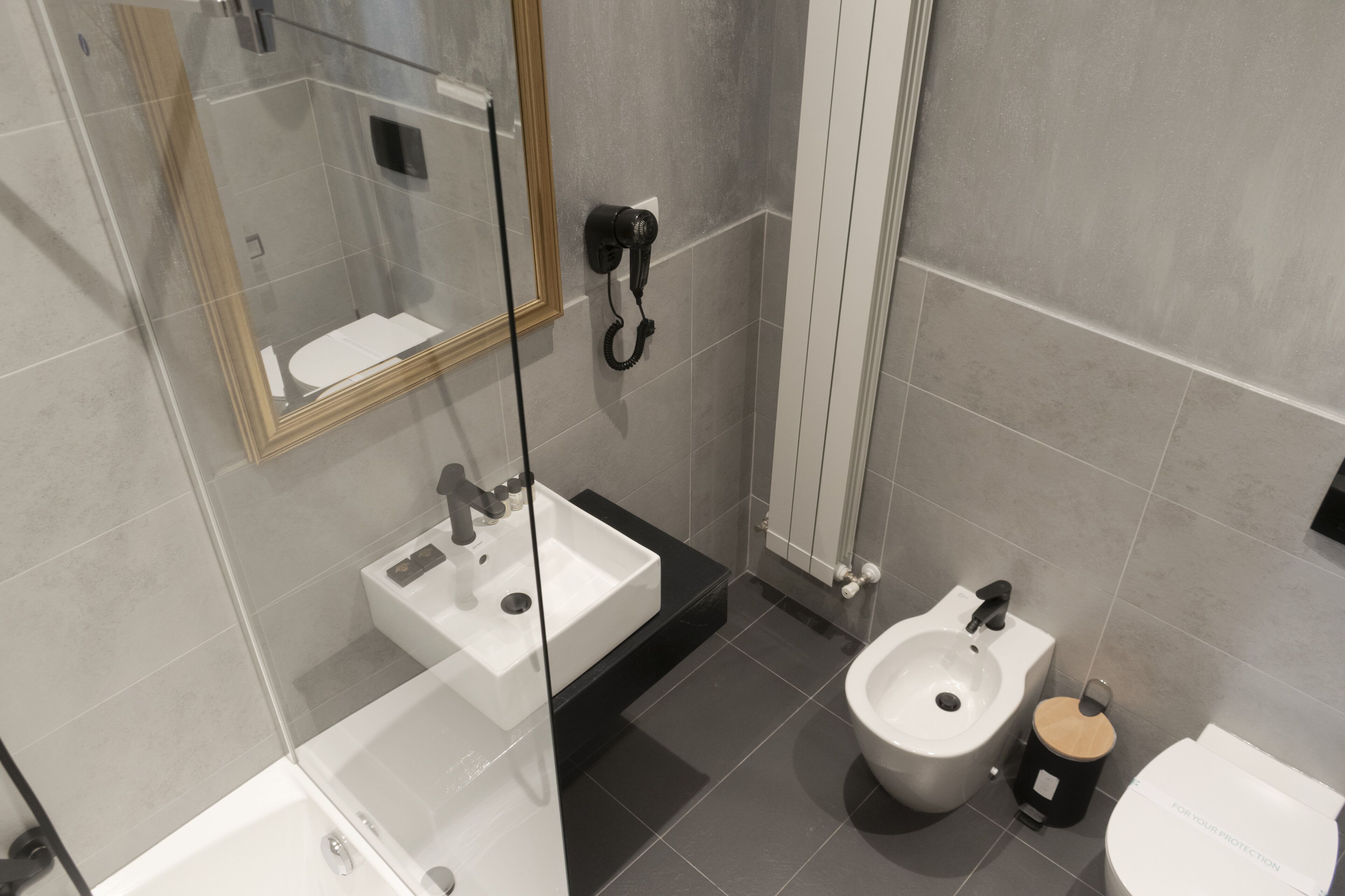 Uma casa de banho moderna com cabine de duche em vidro, uma sanita branca, um bidé e uma casa de wc.