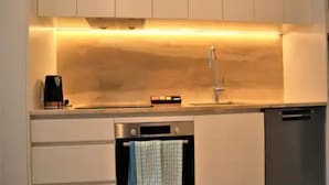Uma cozinha moderna com armários brancos, uma pia de aço inoxidável e um forno embutido.