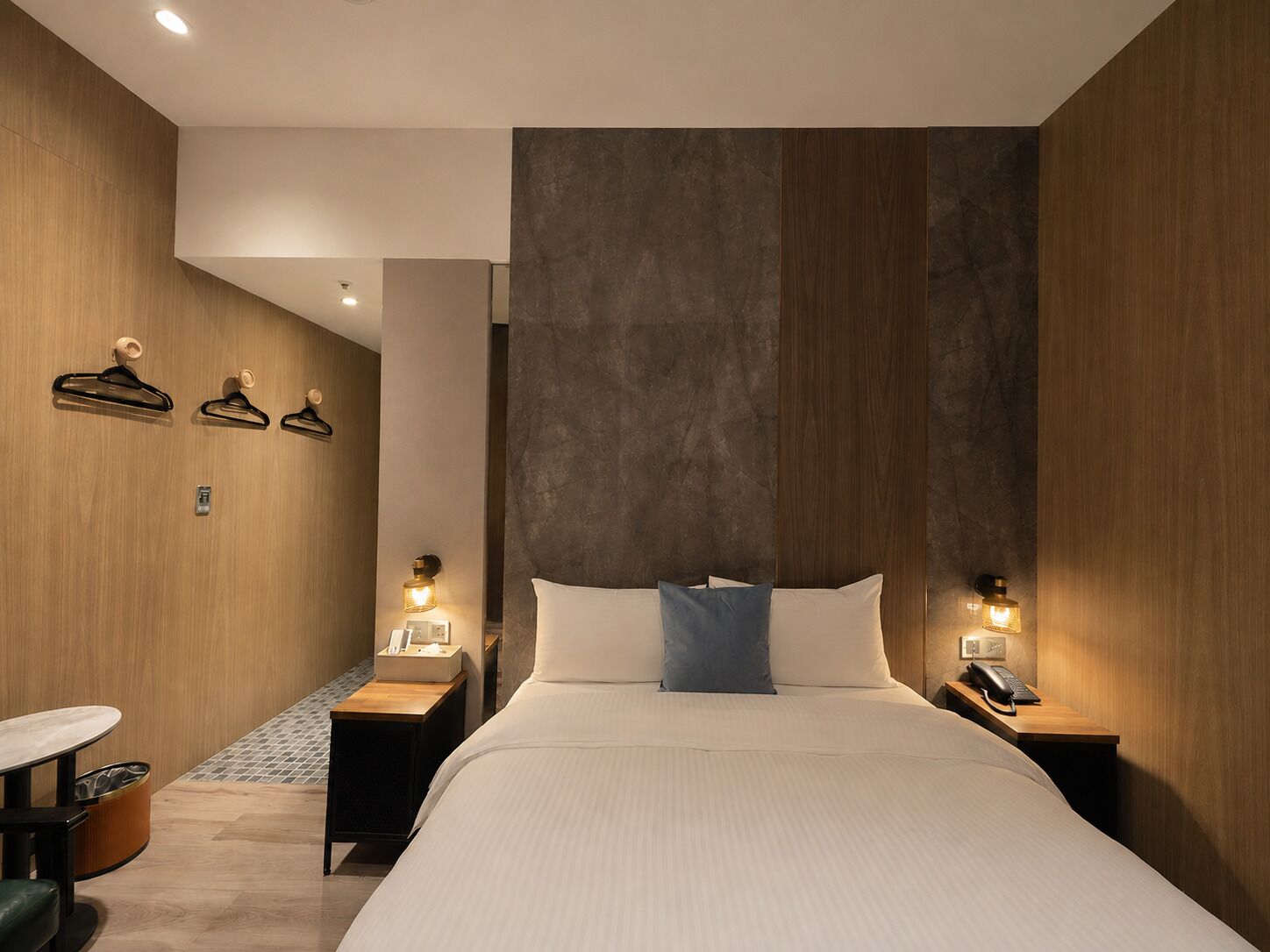Quarto de hotel com uma cama grande, mesas de cabeceira, uma escrivaninha e uma cadeira.