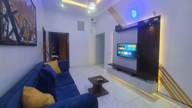 Uma sala de estar moderna com um sofá azul, uma mesa de centro e uma TV de tela plana na parede.