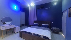 Quarto com cama, penteadeira, espelho e luminária no teto.