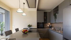 Uma cozinha moderna com ilha central, eletrodomésticos embutidos e iluminação pendente.