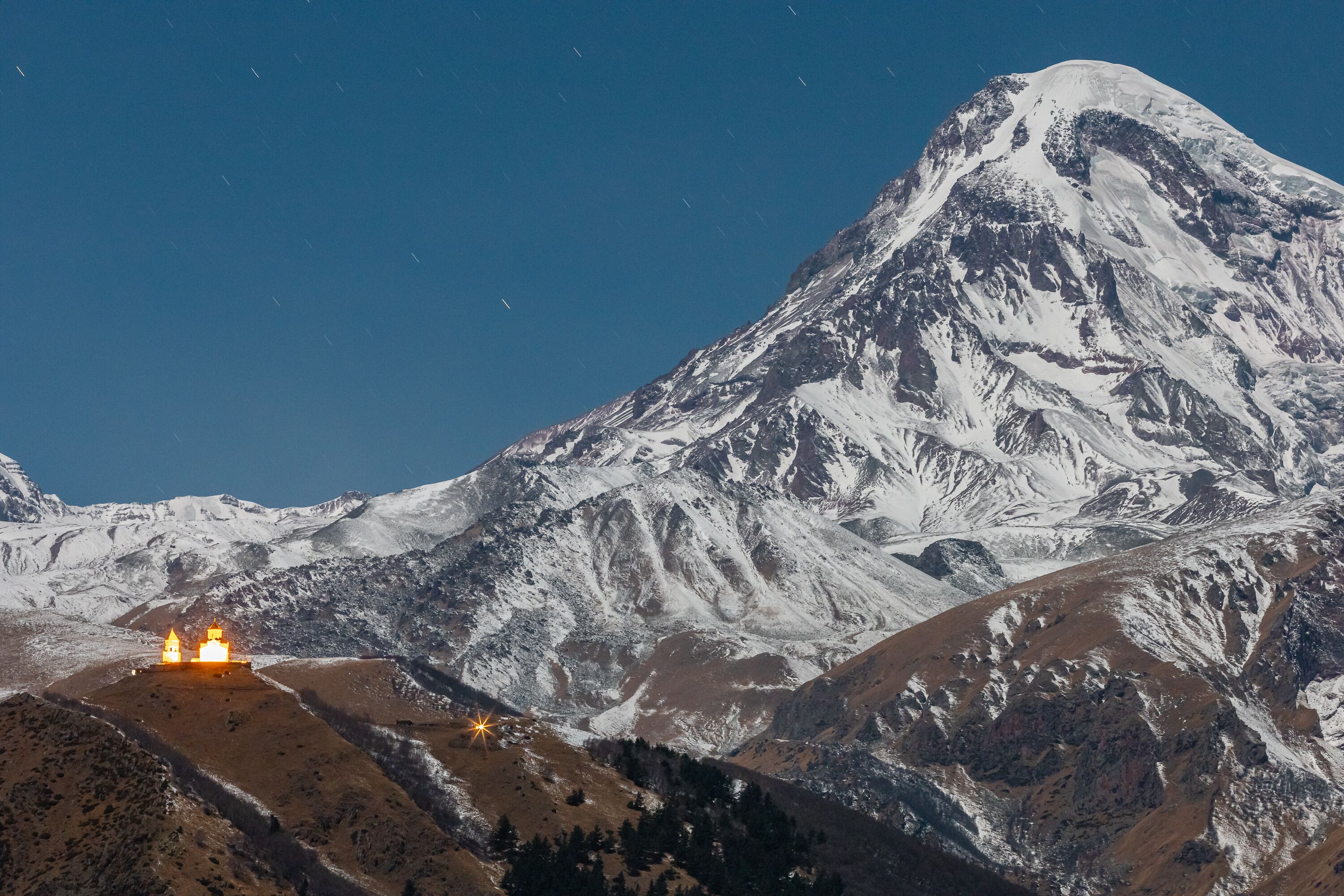 Montanha coberta de neve com uma estrutura iluminada na base.