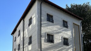 Um edifício de vários andares com fachada moderna, várias janelas e um carro estacionado em frente.