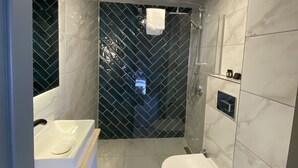 Um banheiro moderno com chuveiro em box de vidro, pia branca e vaso sanitário.