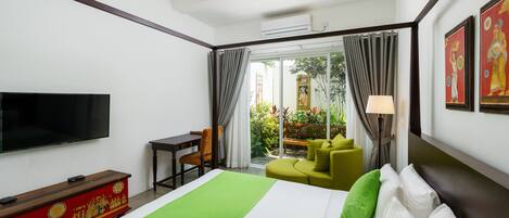 Quarto de hotel com cama, televisão, escrivaninha, poltrona, sofá e vista para o exterior.
