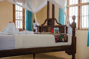 Uma cama bem arrumada com lençóis brancos, um cobertor colorido e uma cabeceira de madeira.
