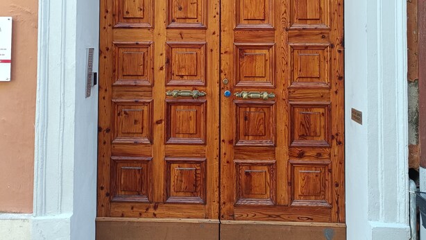 Uma porta dupla de madeira com puxador de metal e olho mágico.