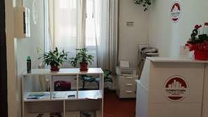 Um quarto com escrivaninha, prateleiras, impressora e uma planta em vaso.