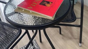 A round glass table with a red book titled "Vienna" and a potted plant.