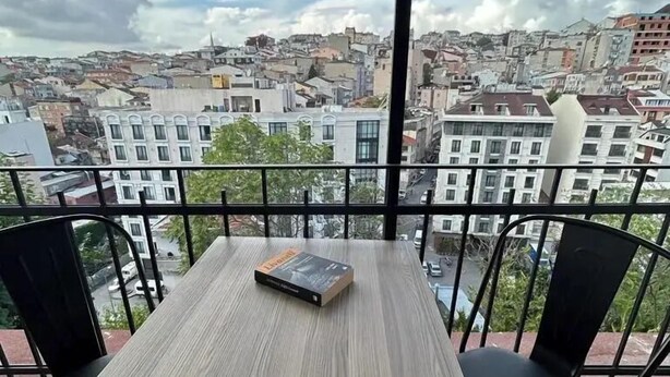 Varanda com mesa e duas cadeiras, vista para a cidade.