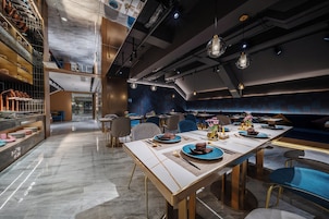 Um restaurante moderno com uma mesa de jantar comprida, cadeiras e uma variedade de pratos.