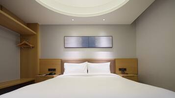 Quarto de hotel moderno com uma cama grande, cabeceira de madeira, mesas de cabeceira, uma obra de arte na parede e um claraboia circular.