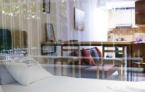 Quarto com uma cama, uma cadeira, uma mesa e vista pela janela.