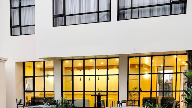 Um hotel com piscina, área de estar externa e um edifício com várias janelas.