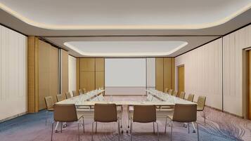 Uma sala de conferência com uma mesa comprida, cadeiras e uma tela grande.