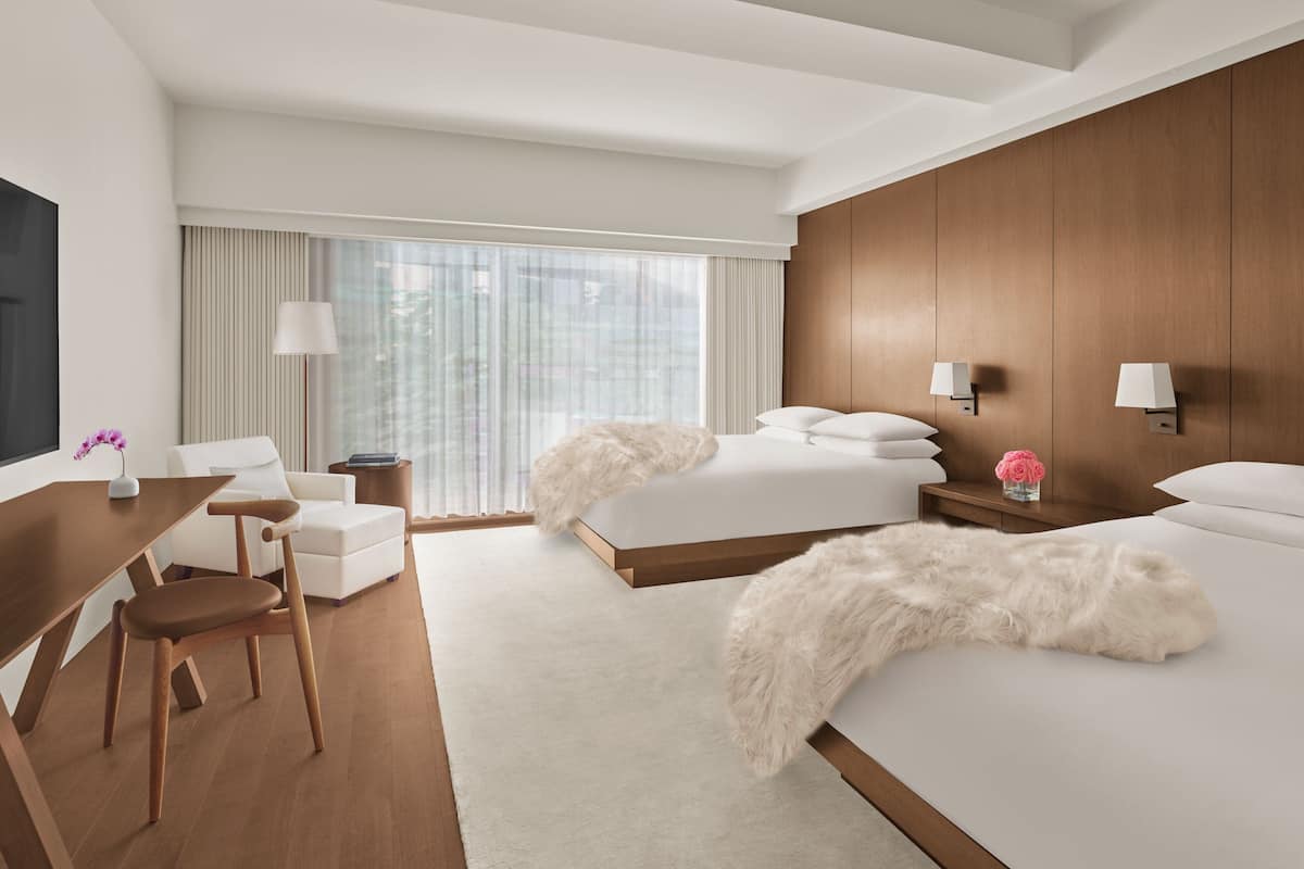 Quarto de hotel moderno com uma cama grande, uma mesa, uma cadeira e um sofá.
