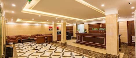 Um saguão de hotel com balcão de check-in, área de estar e piso estampado.
