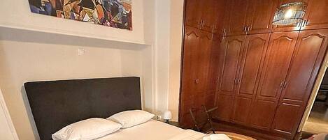 Quarto com uma cama, mesa de cabeceira, guarda-roupa e um quadro na parede.