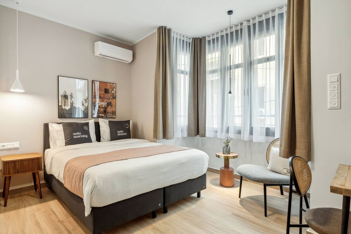 Quarto moderno com uma cama grande, uma mesa de cabeceira, uma cadeira e uma pequena mesa.