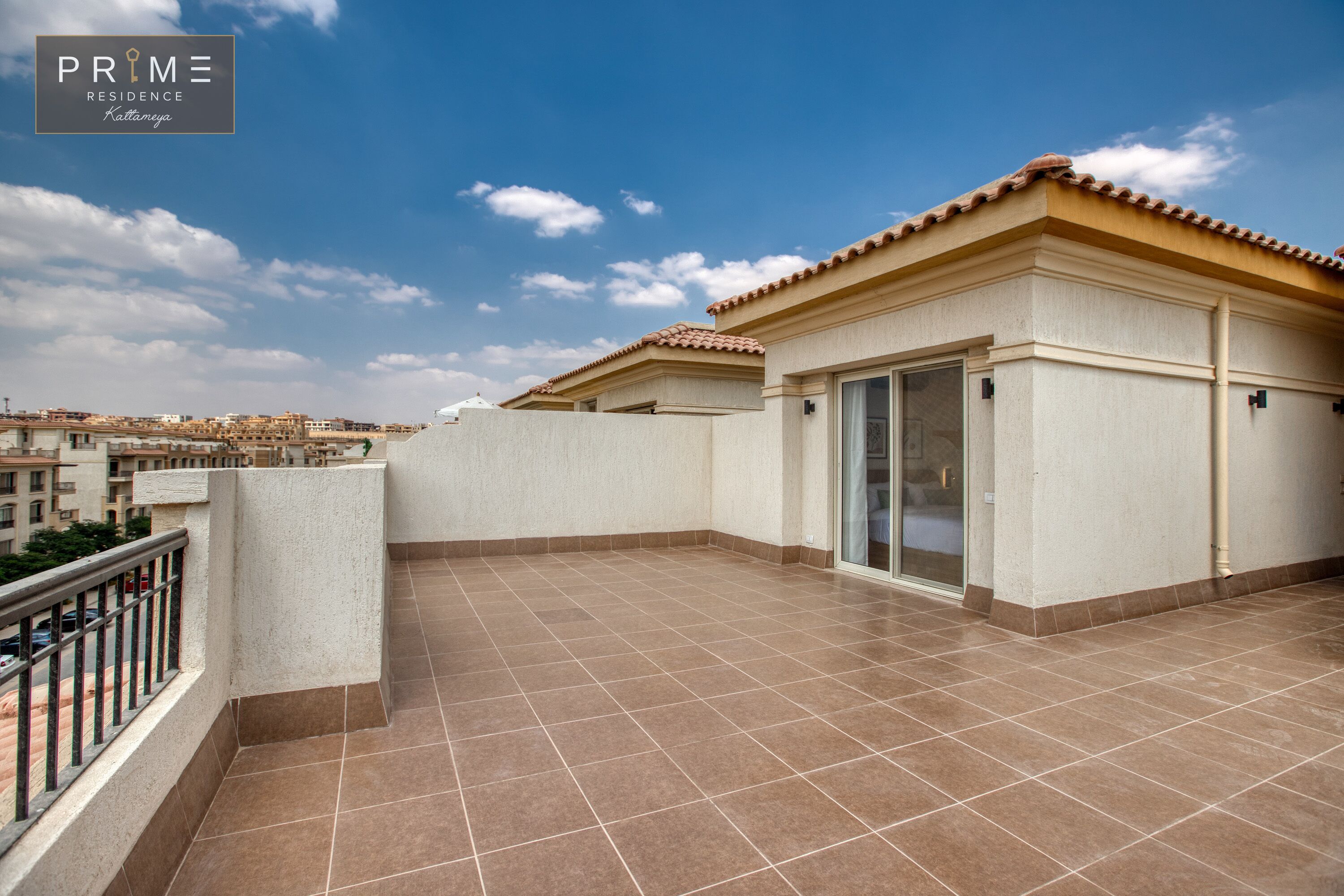 Um imóvel residencial com varanda e telhado em azulejos, e vista para edifícios vizinhos.