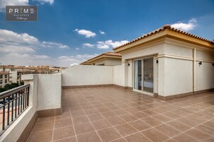 Um imóvel residencial com varanda e telhado em azulejos, e vista para edifícios vizinhos.