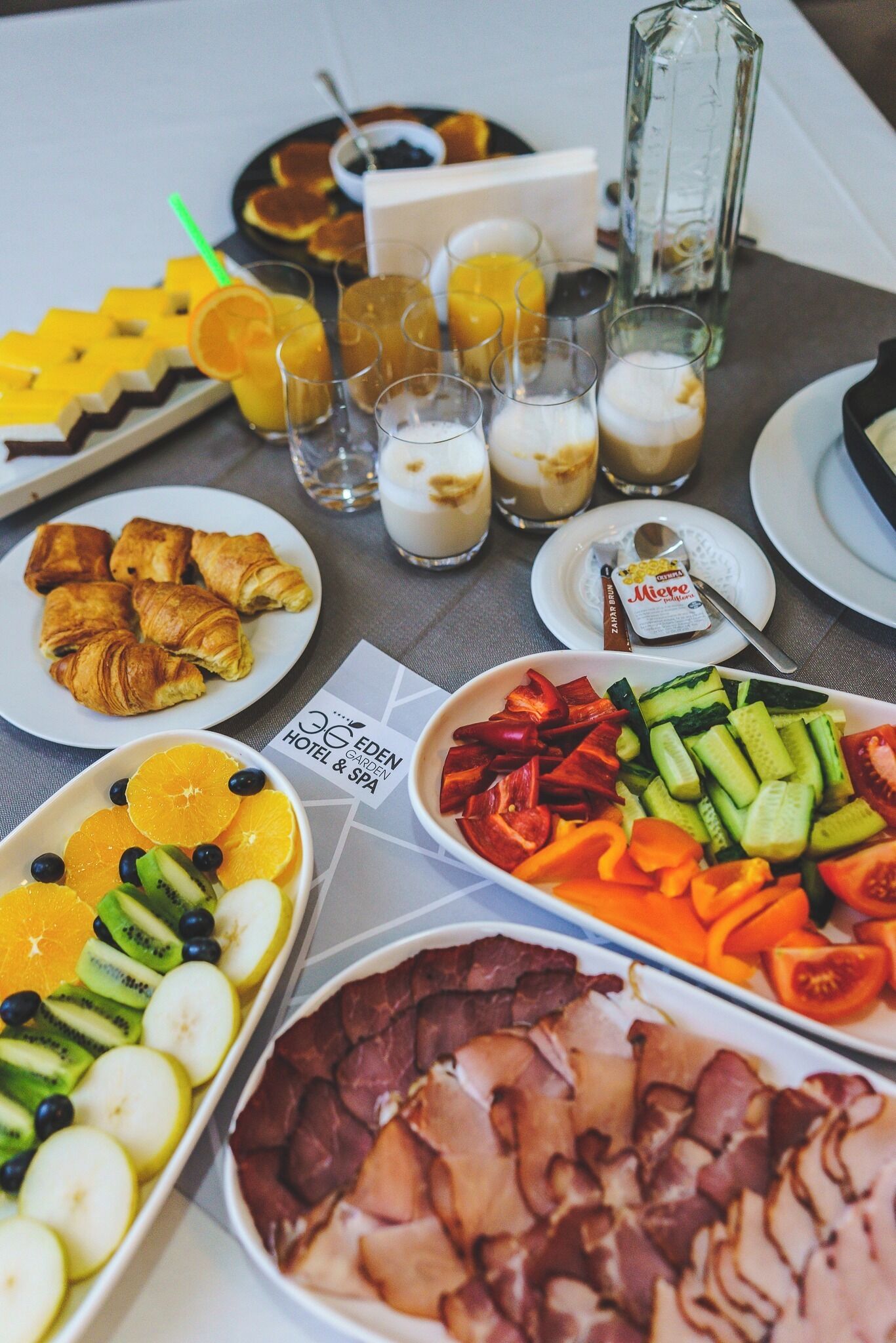 Um buffet de café da manhã com diversos pratos, incluindo croissants, frutas, vegetais e carnes.