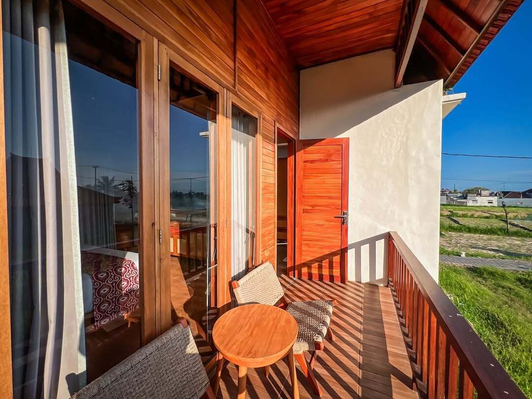 Um deck de madeira com uma mesa redonda e duas cadeiras, grandes portas de vidro deslizantes e vista do horizonte.