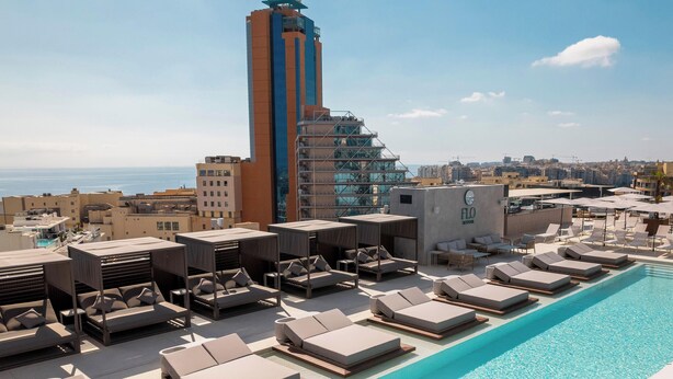 Área de piscina no terraço, com espreguiçadeiras e vista para a cidade.