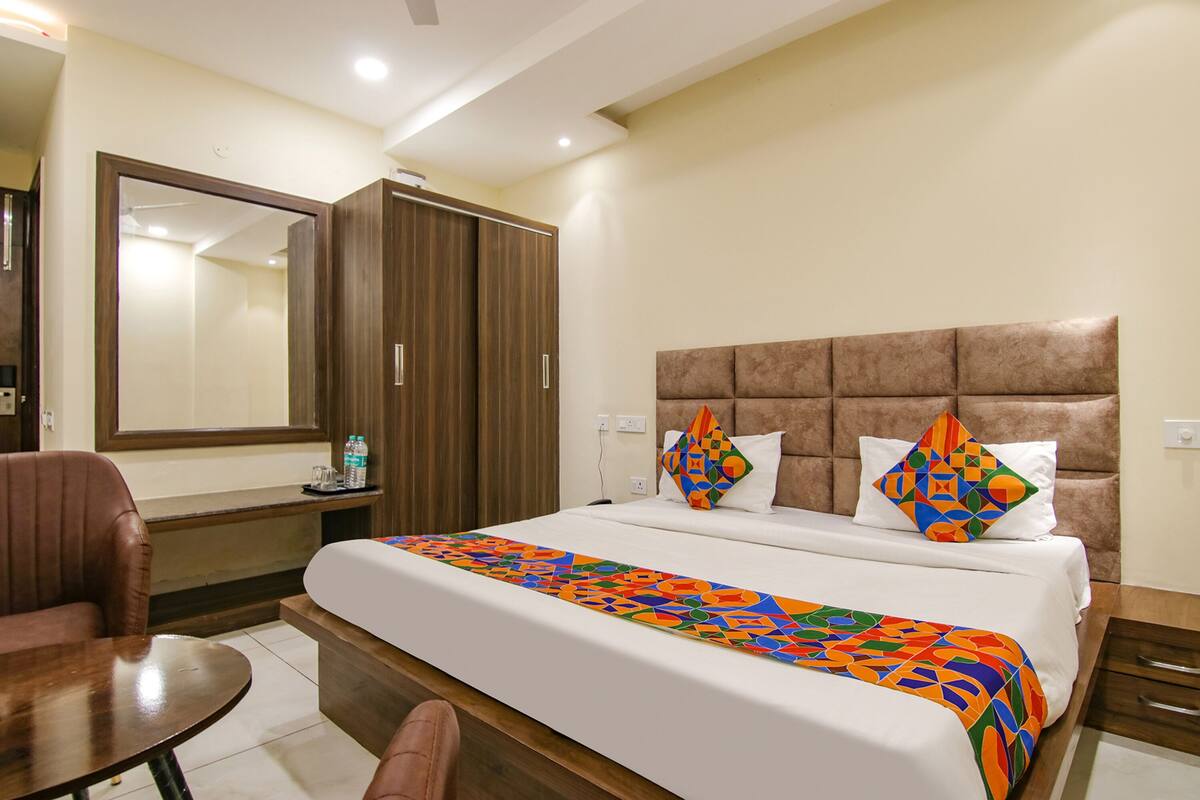 Quarto de hotel com cama, cadeira, escrivaninha e guarda-roupa.