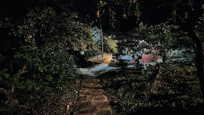 Uma trilha de pedra serpenteia por um jardim à noite, com um edifício ao fundo.