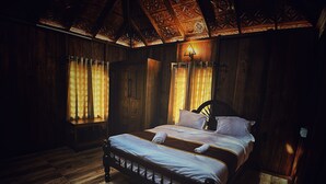 Quarto com cama de madeira, cortinas e teto inclinado.