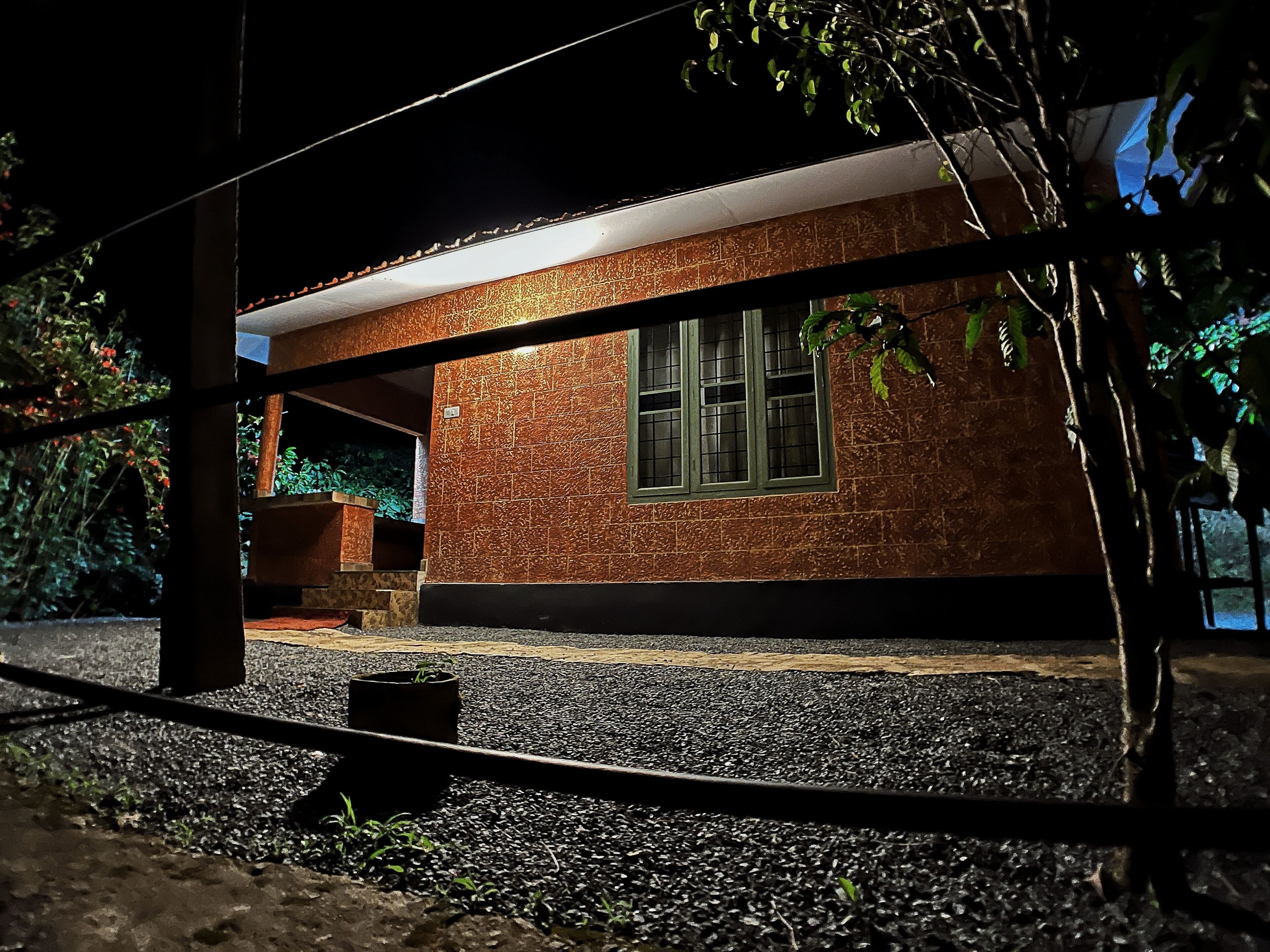 Um edifício com fachada de tijolos, janela com padrão quadriculado e piso de cascalho.