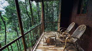 Um deck de madeira com guarda-corpo, duas cadeiras de vime e uma mesa.