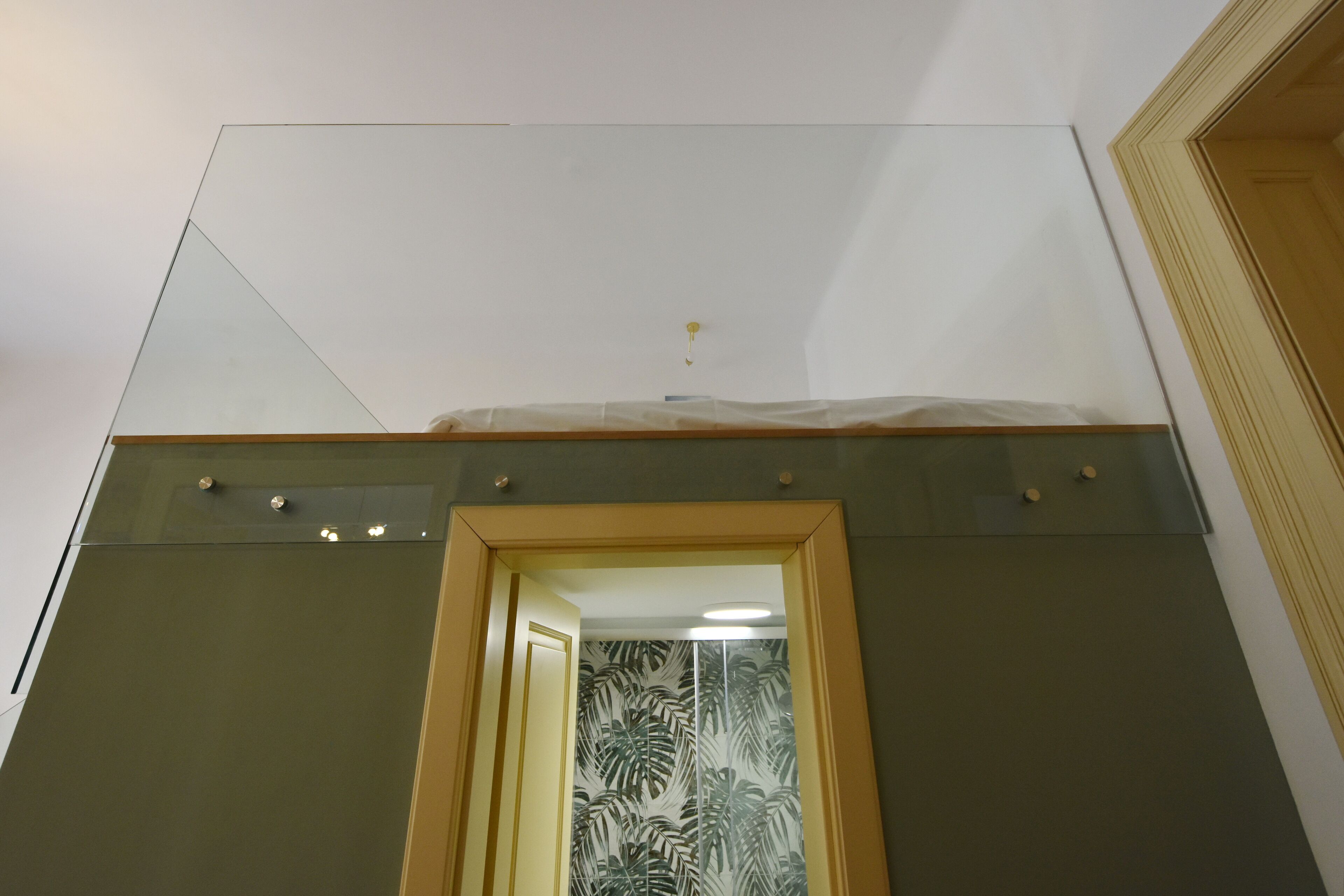 Um quarto com parede espelhada, moldura de porta em madeira e teto com iluminação embutida.