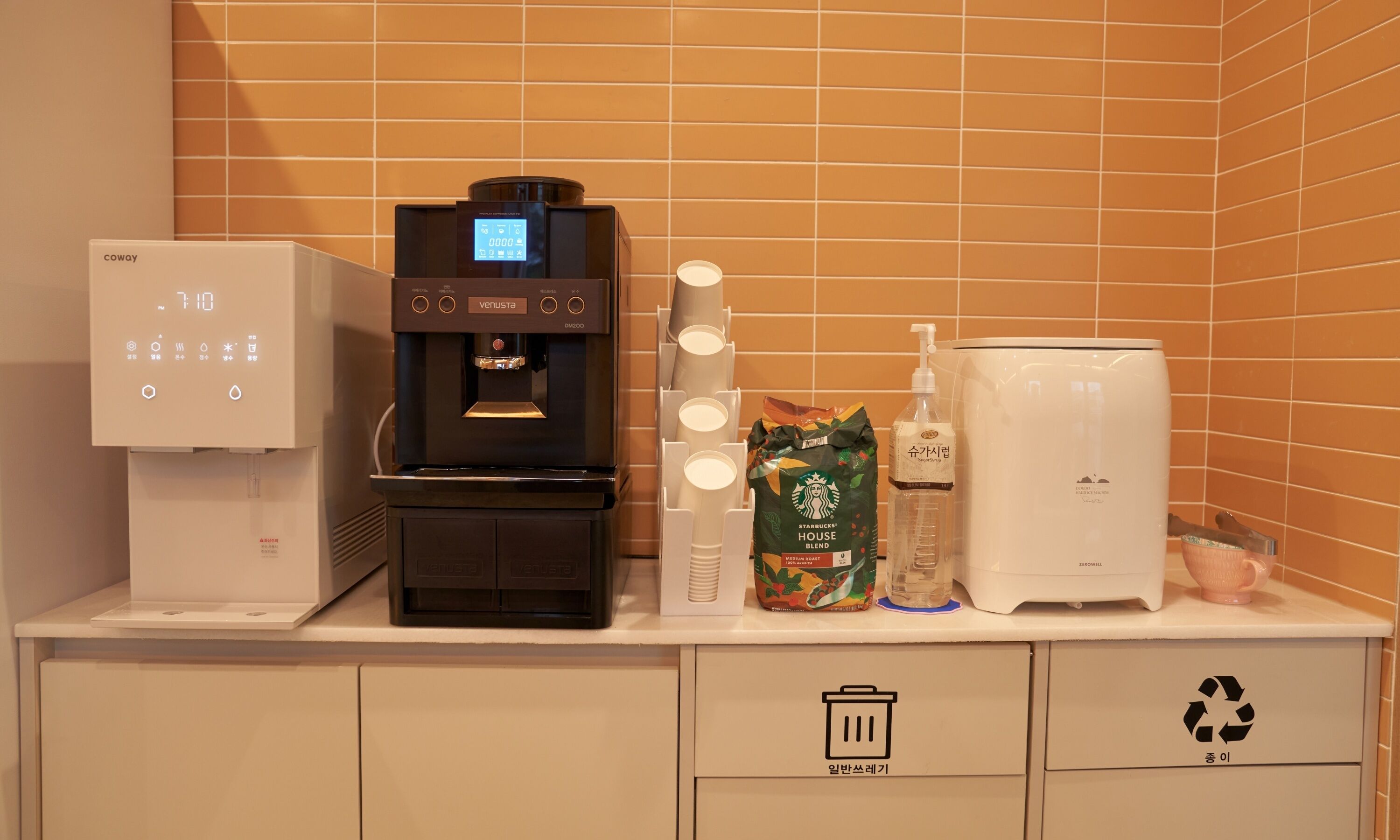 Uma estação de café com máquina de café, dispensador de água, cafeteira e um saco de café Starbucks.