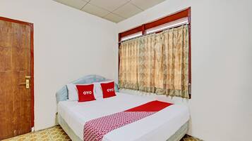 Um quarto com uma cama, porta de madeira e janela com cortinas.