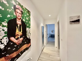 Um corredor com um mural floral na parede, uma porta branca e um pequeno espelho.