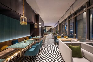 Um interior moderno com uma longa área de jantar, assentos e piso estampado.
